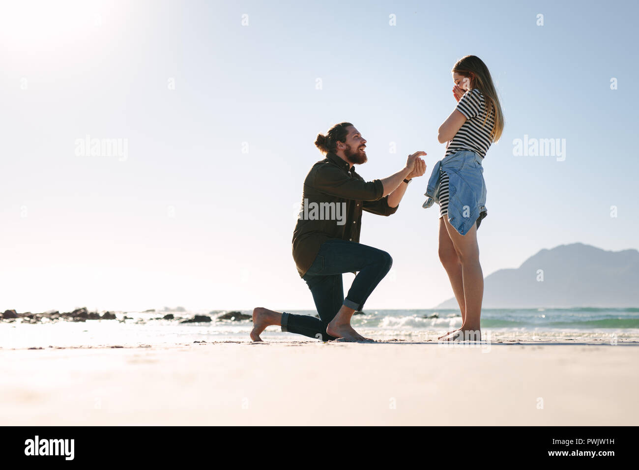 Man down on one knee offering a surprise to woman. Man proposing woman at the beach Stock Photo ...