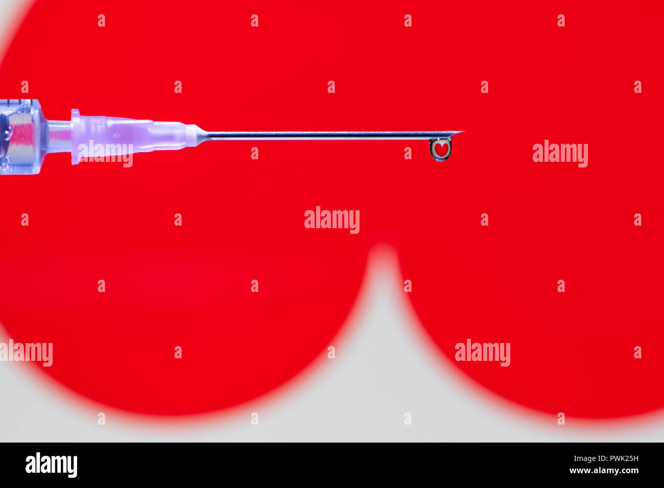 A droplet of vaccine at the tip of the needle and syringe reflecting ...