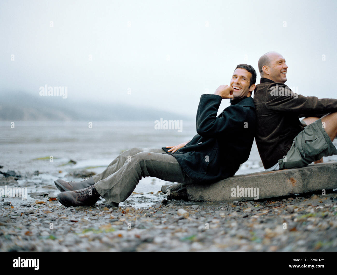 Two men sitting back to back on shoreline Stock Photo - Alamy Two men sitting back to back on shoreline Stock Photo - Alamy