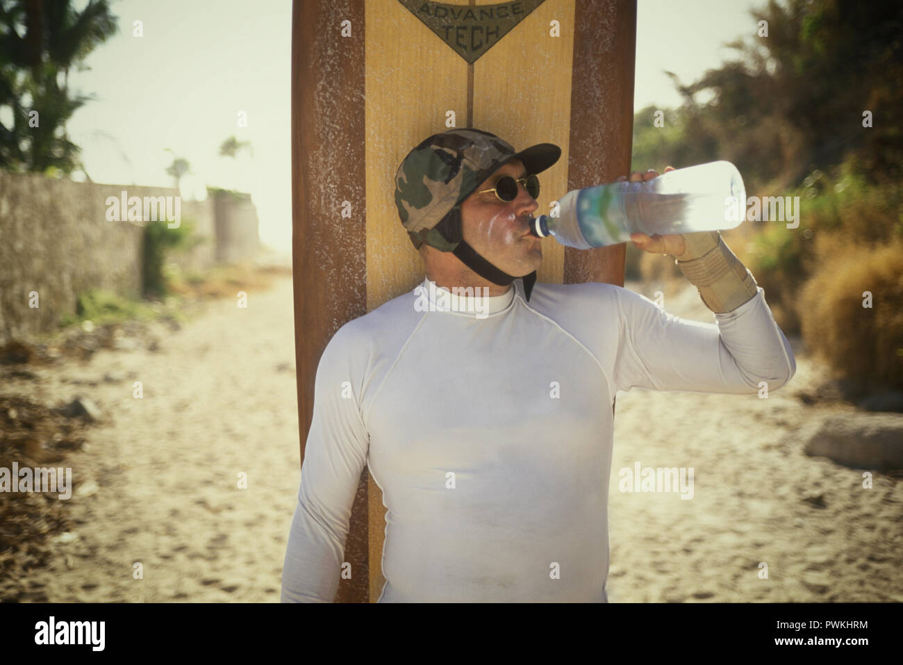 Man drinking water with surfboard Stock Photo - Alamy
