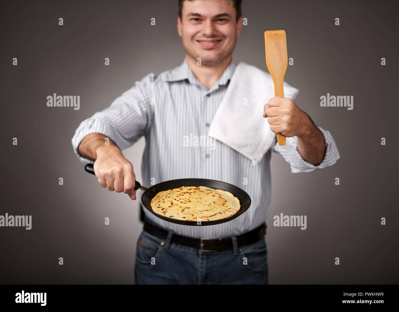 man posing with a pancake in a pan, white shirt and pants, gray ...