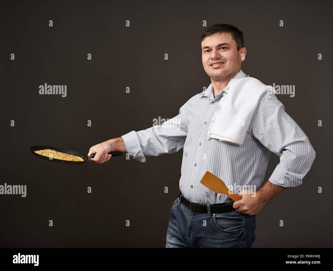 man posing with a pancake in a pan, white shirt and pants, gray ...