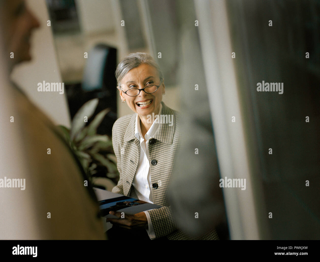 Secretary laughing with her co-worker Stock Photo - Alamy