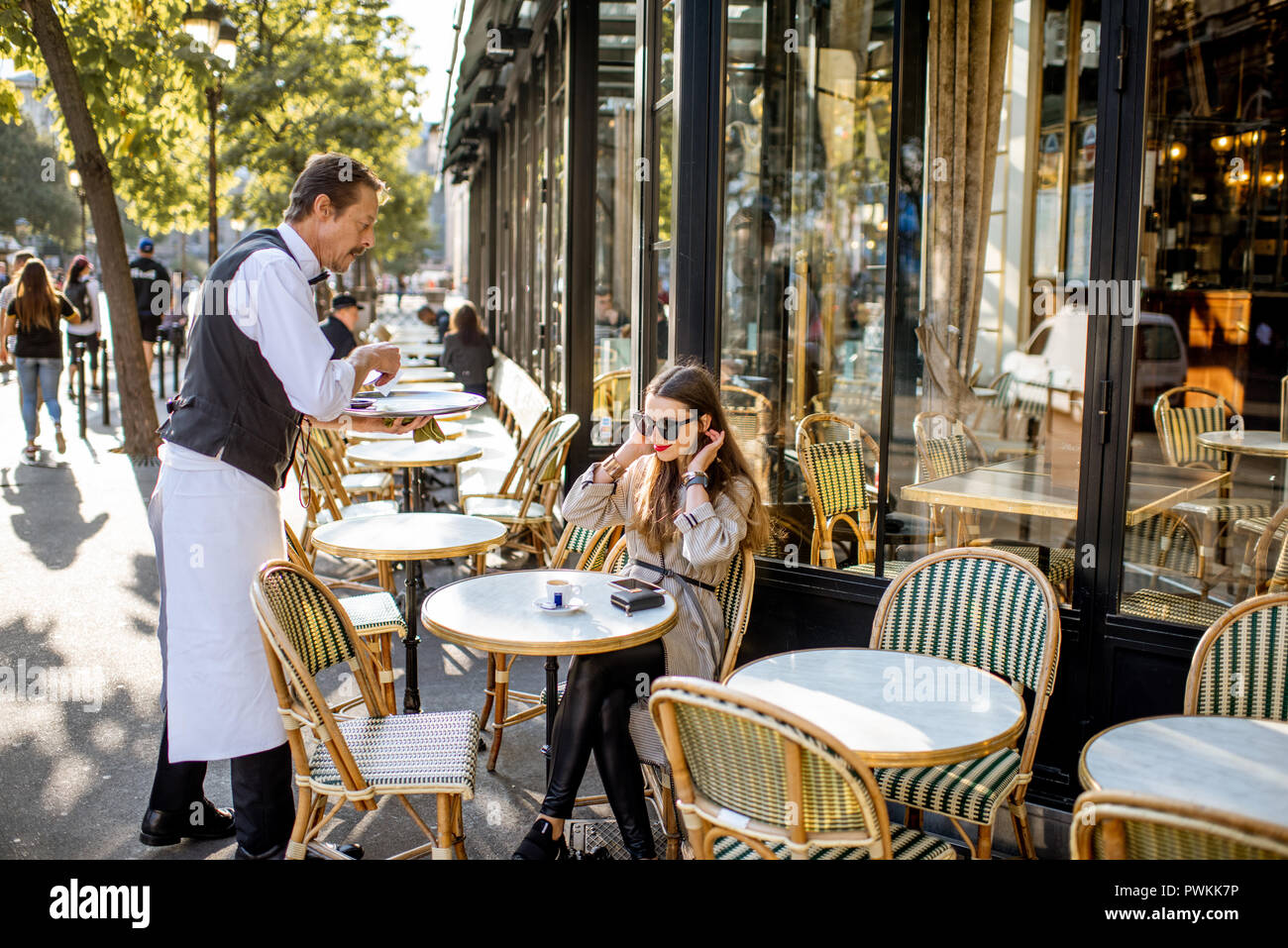 PARIS, FRANCE - August 31, 2018: Waiter serving coffee to a young woman ...