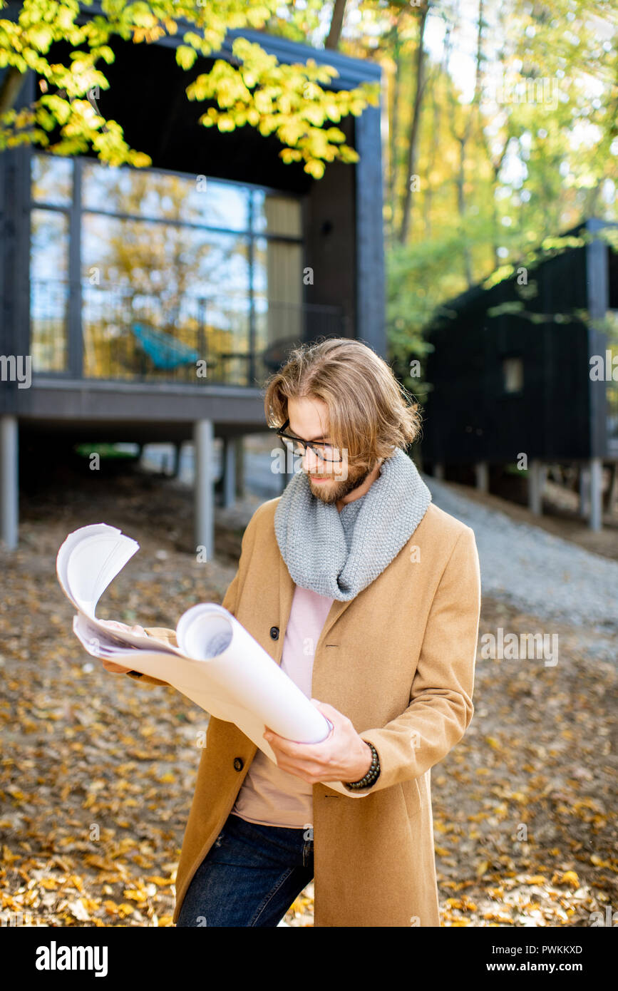 Portrait of a handsome man architect standing with drawings in front of ...