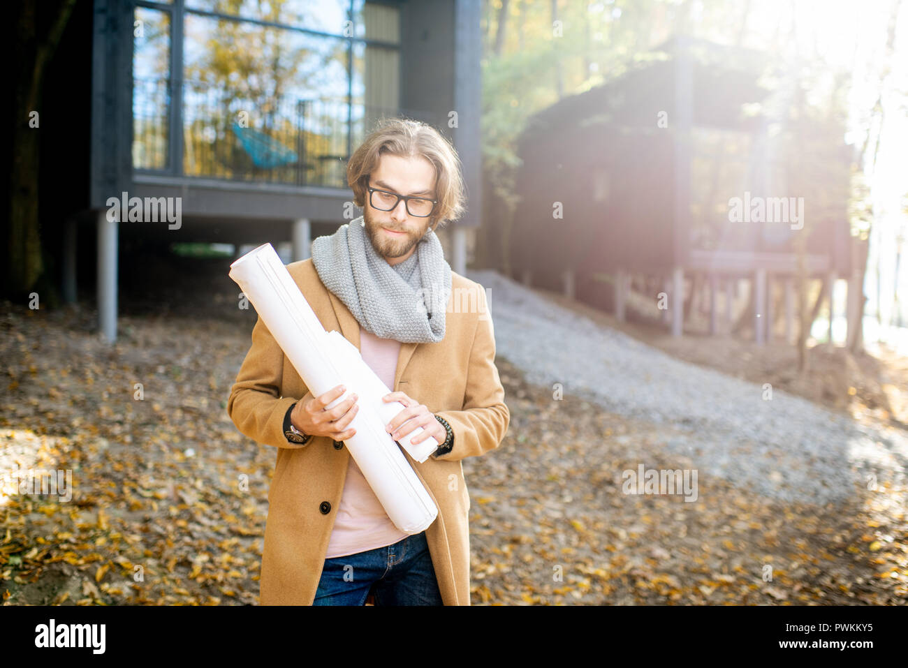 Portrait of a handsome man architect standing with drawings in front of ...