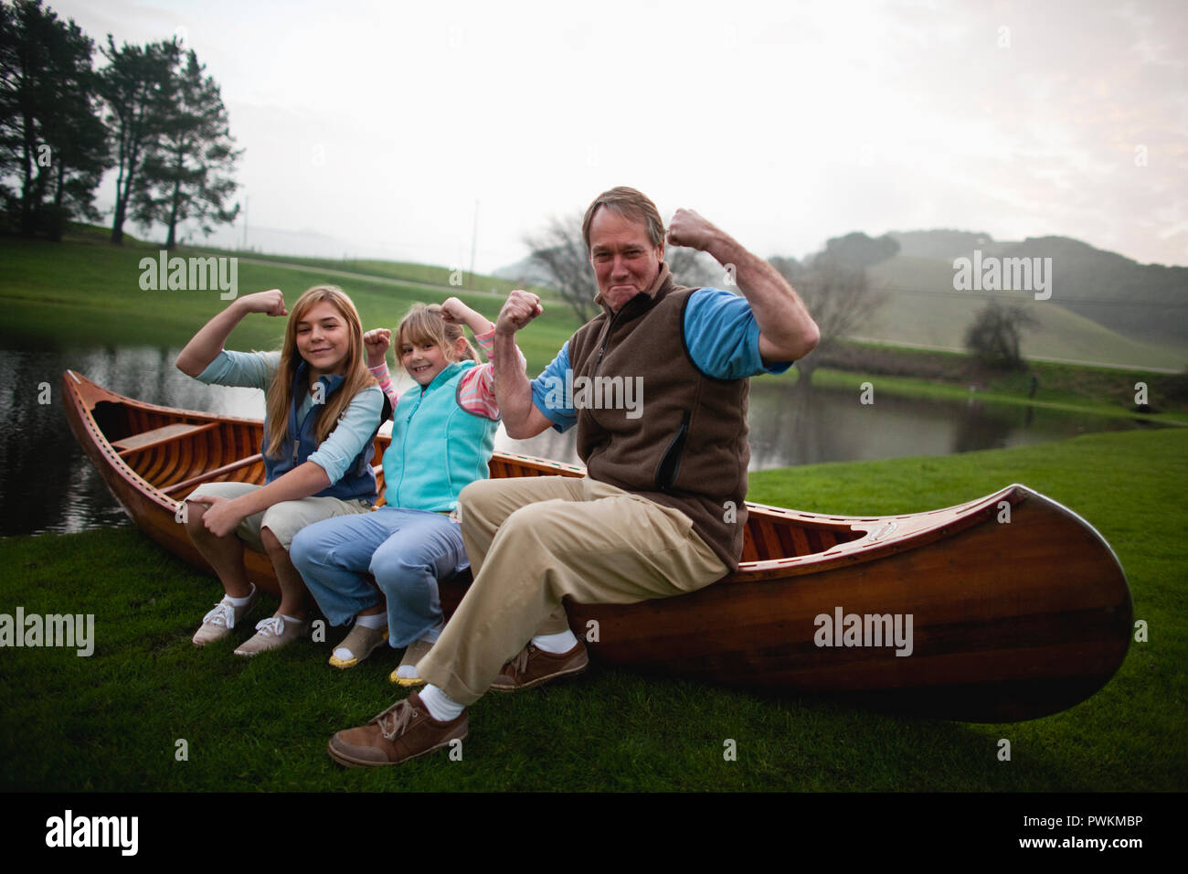 Family flexing muscles sitting on canoe Stock Photo - Alamy