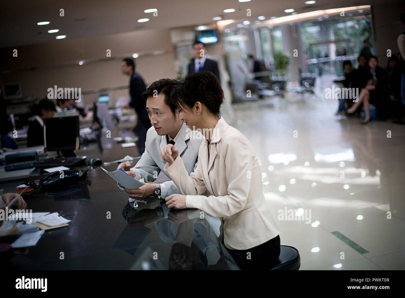 Mid-adult couple sitting at a bank desk Stock Photo - Alamy
