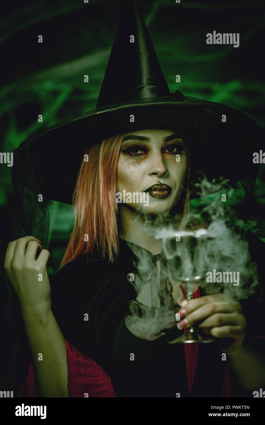 Witch with awfully face in creepy surroundings and smoky green ...