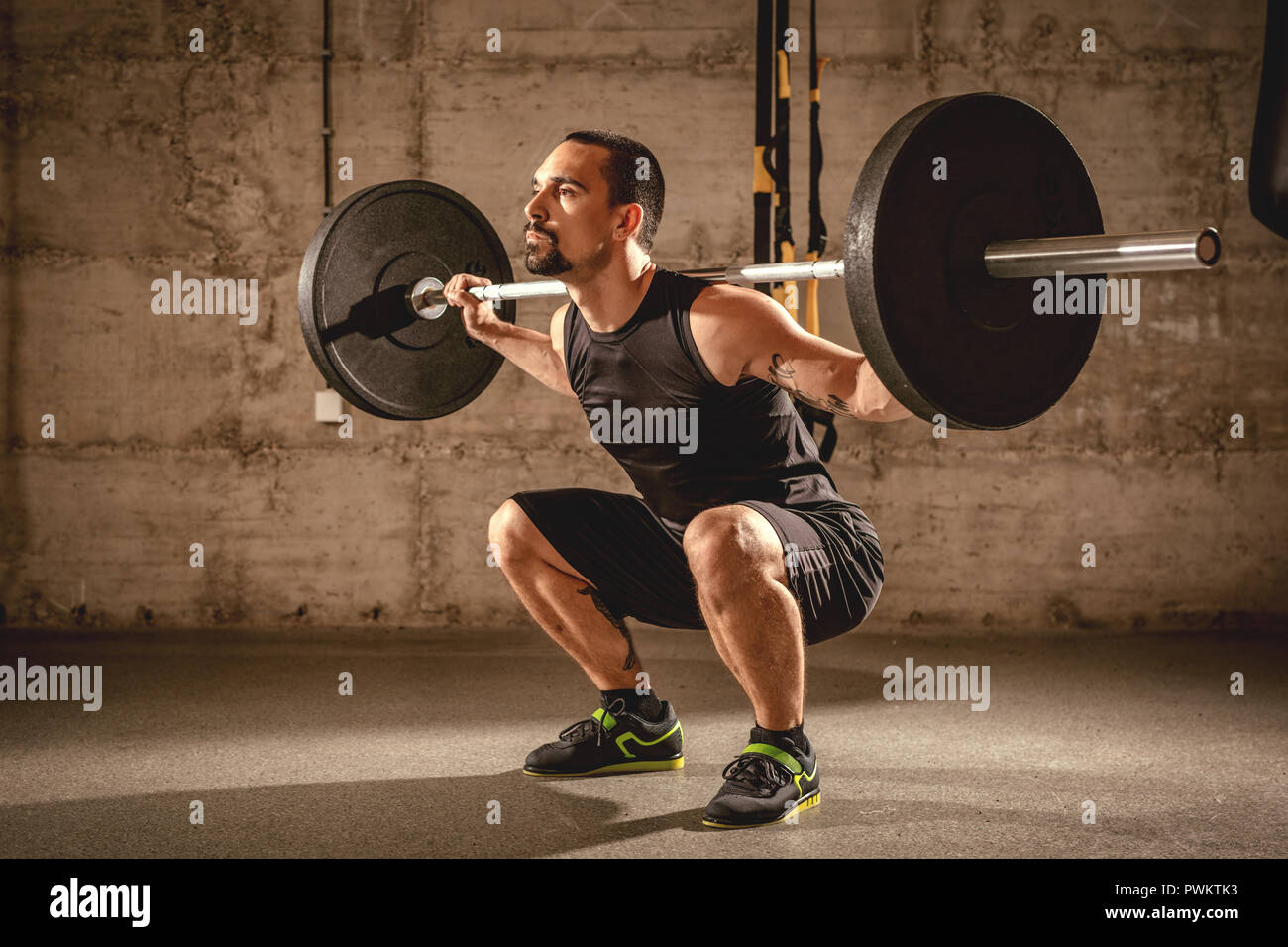 Handsome young muscular man doing squat exercise with barbell at the ...