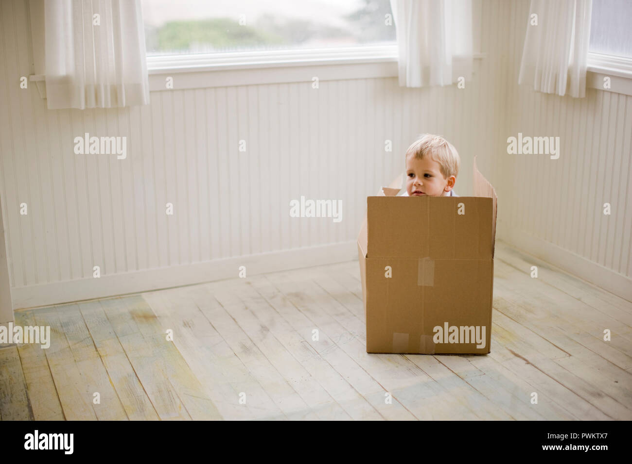 Young boy sitting inside a cardboard box Stock Photo - Alamy