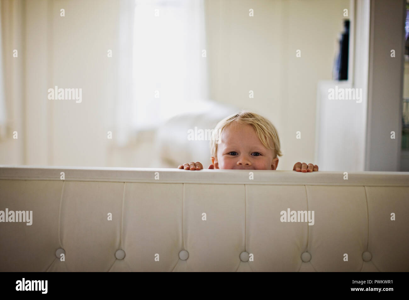 Little boy peeking over back of couch Stock Photo - Alamy