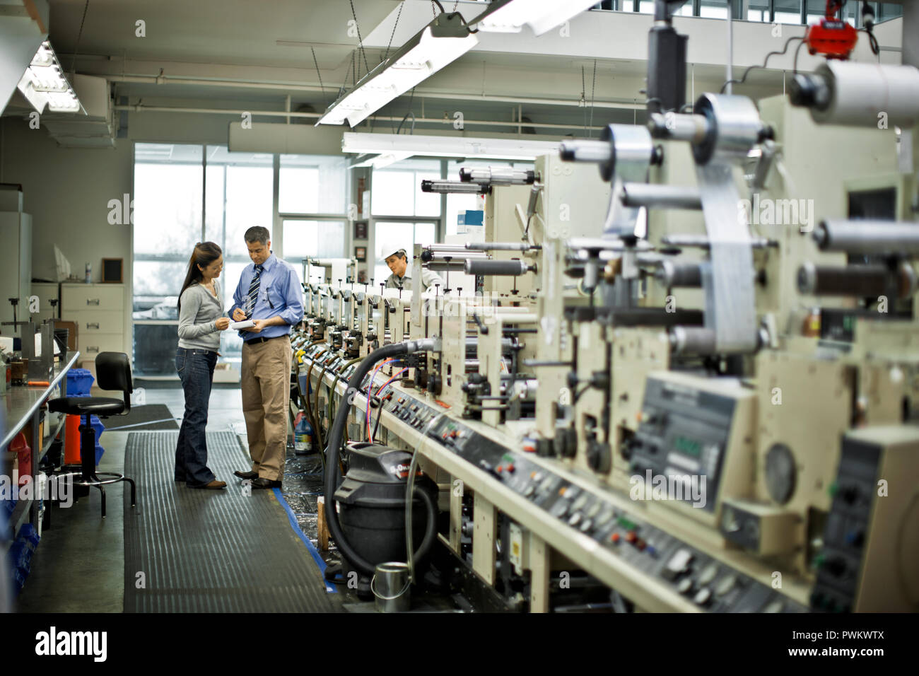 Business colleagues consulting notes in a factory Stock Photo - Alamy