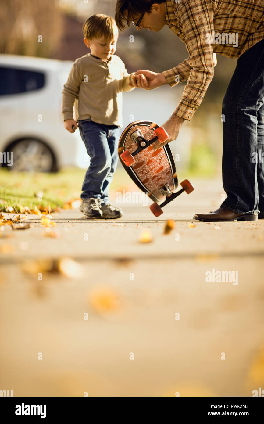 Father helping son with skateboard Stock Photo - Alamy