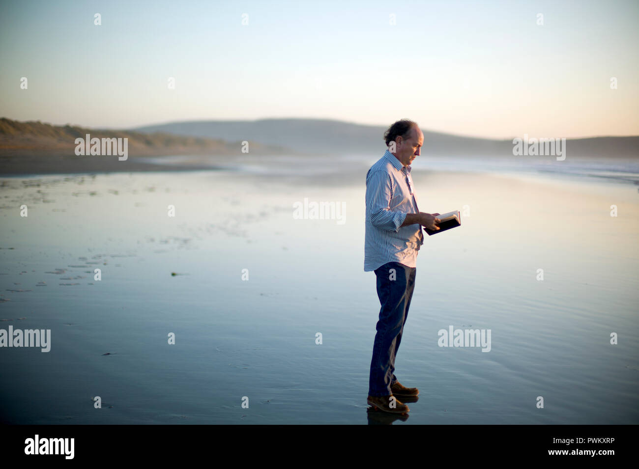 Man reading a book at the beach Stock Photo - Alamy
