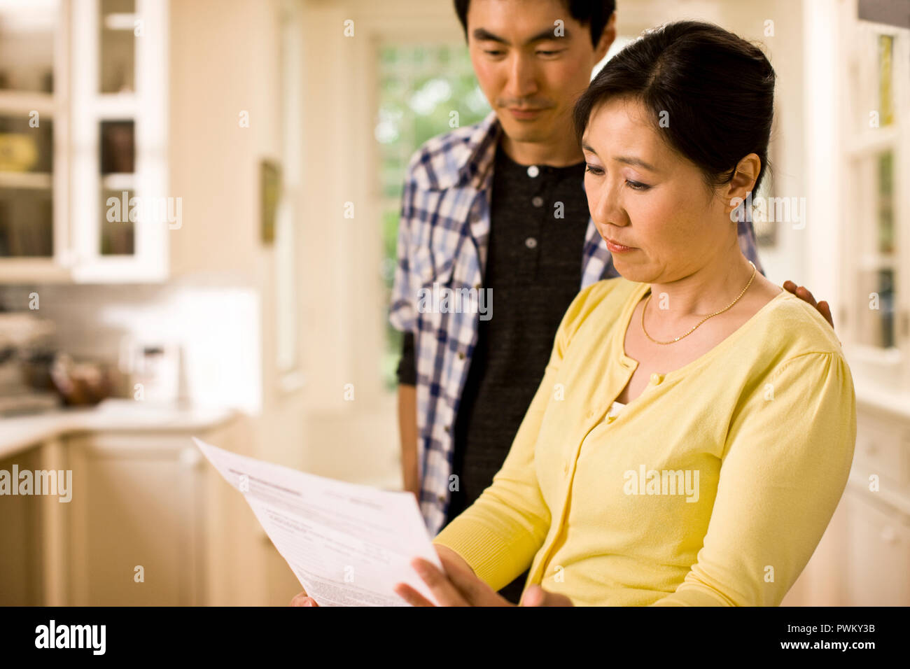 Adult son standing in a kitchen with his mother and looking at ...