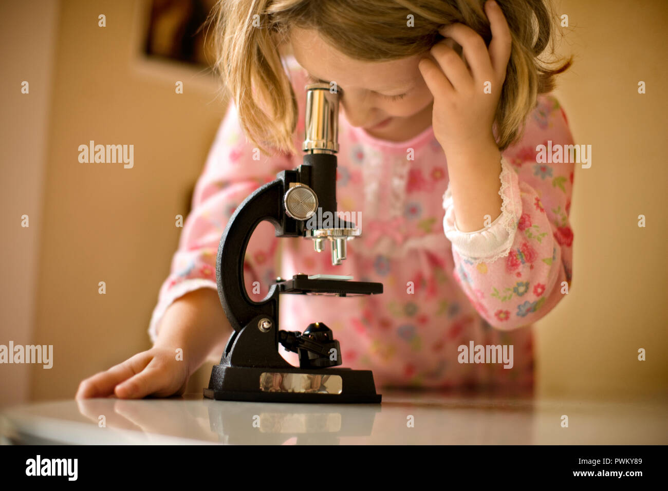 Girl looking through a microscope Stock Photo - Alamy