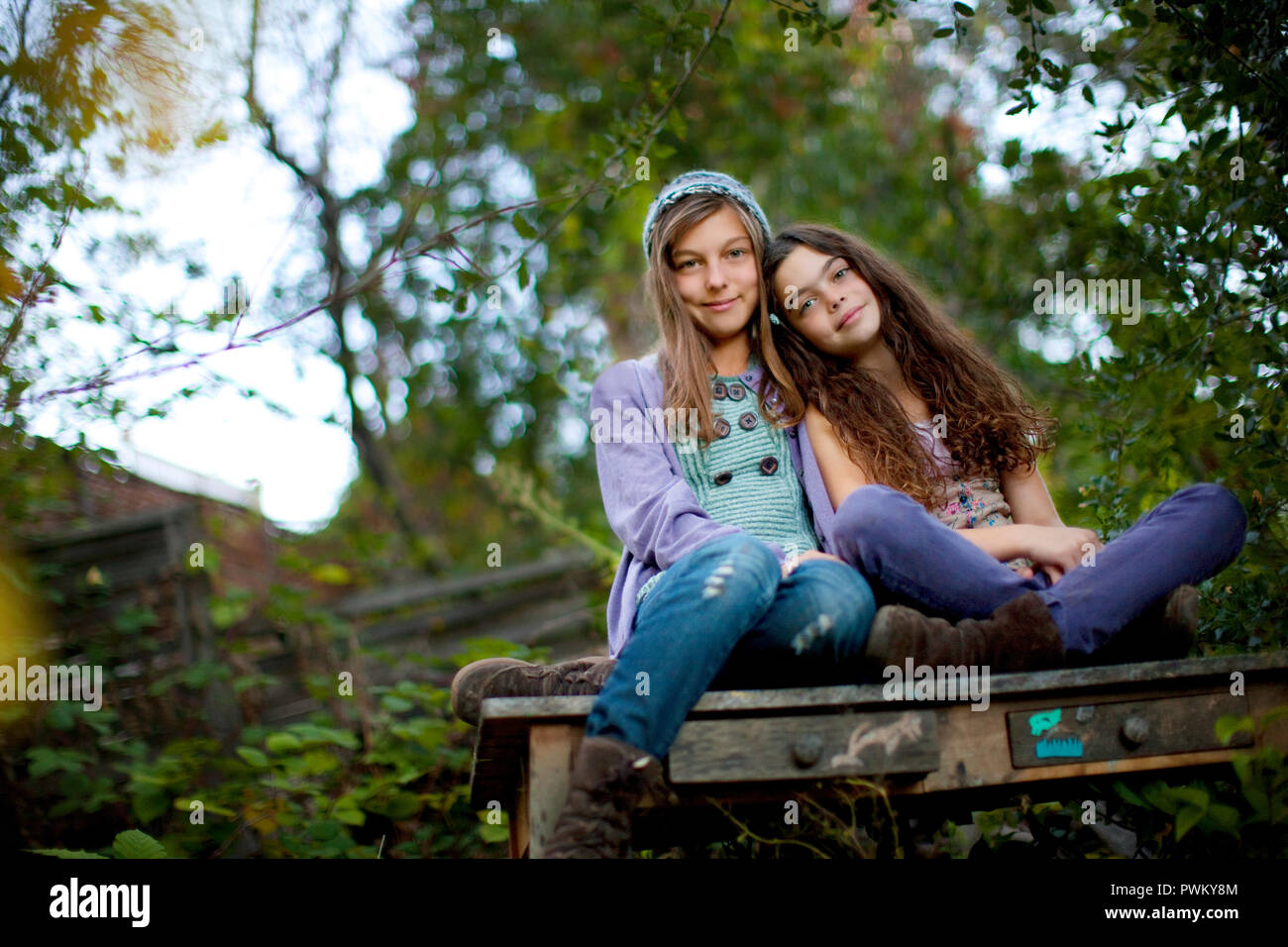 Two friends sitting on a worn desk Stock Photo - Alamy