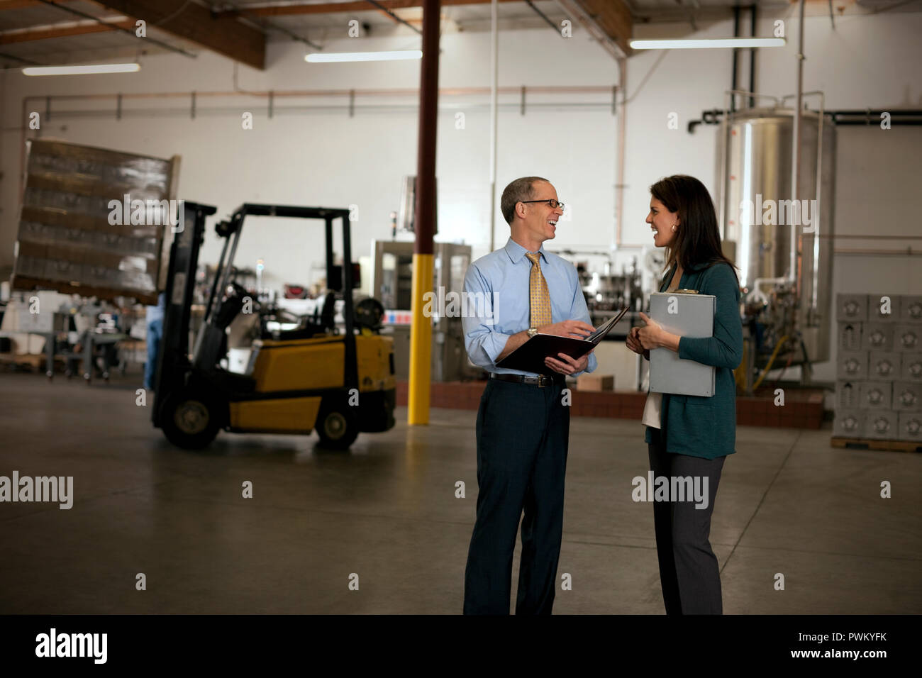 Two smiling colleagues discussing work in a warehouse Stock Photo - Alamy