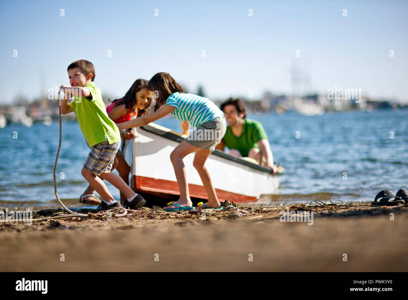 Family at beach with row boat Stock Photo - Alamy