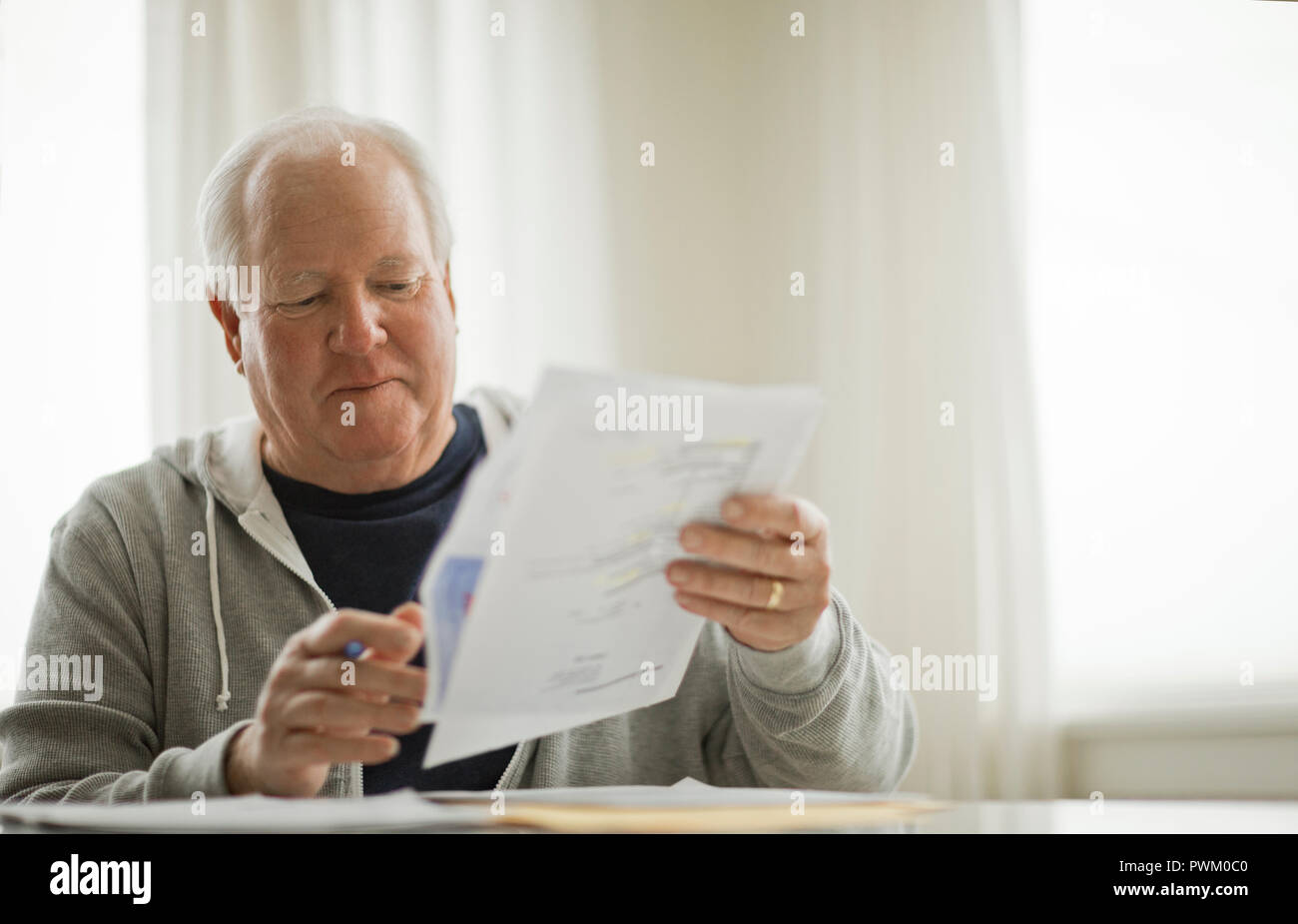Senior man looking over important documents Stock Photo - Alamy