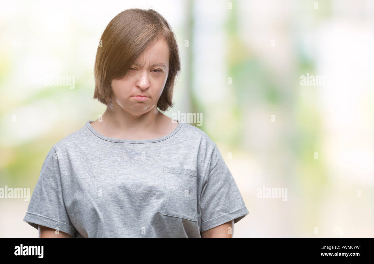 Young adult woman with down syndrome over isolated background depressed ...