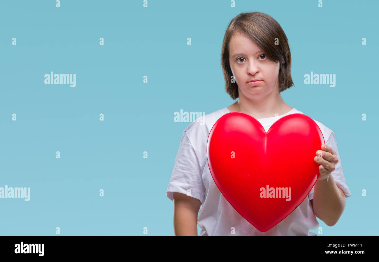 Young adult woman with down syndrome holding red heart over isolated ...