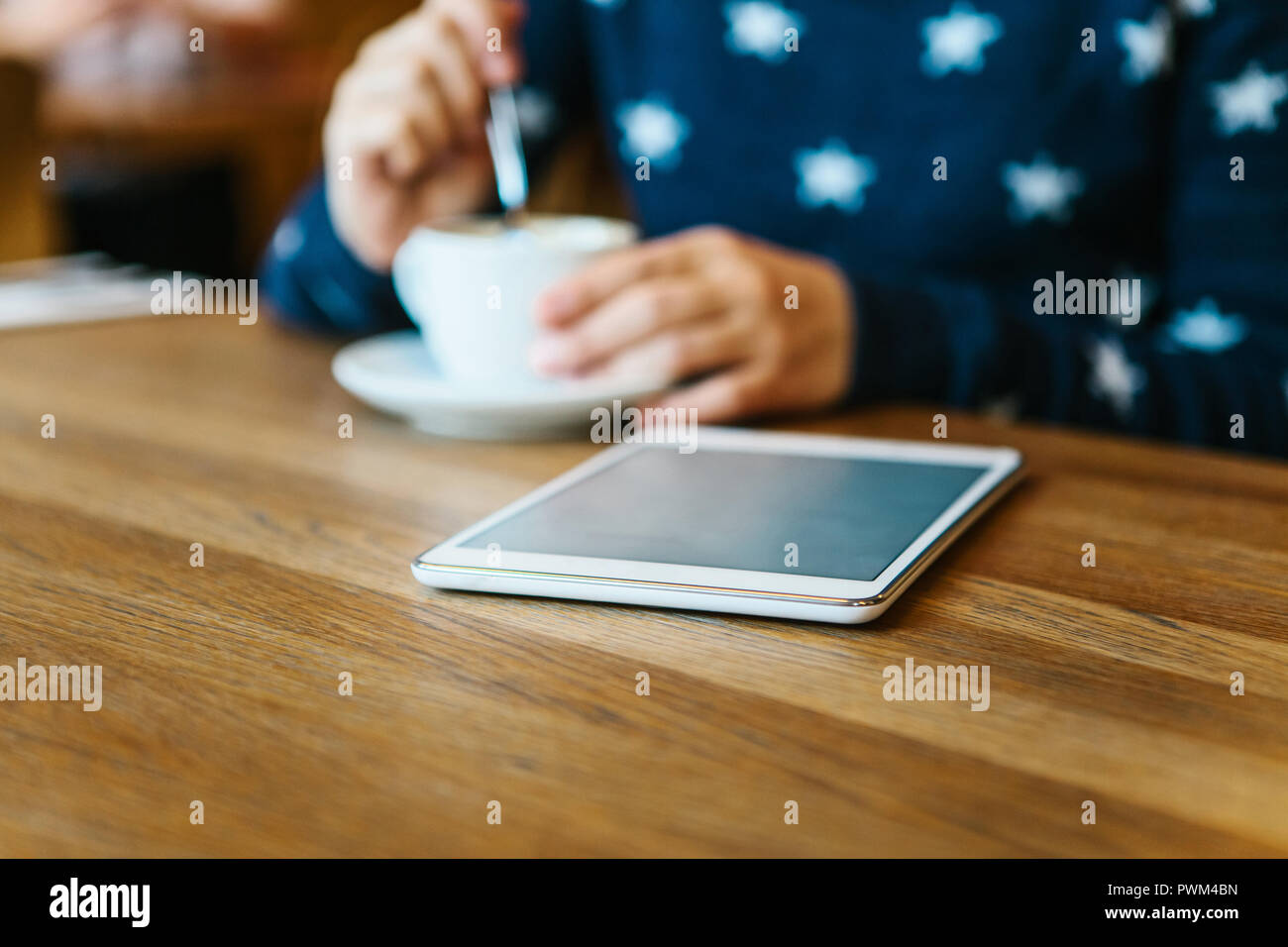 A girl in a cafe drinks coffee and uses a tablet Stock Photo - Alamy