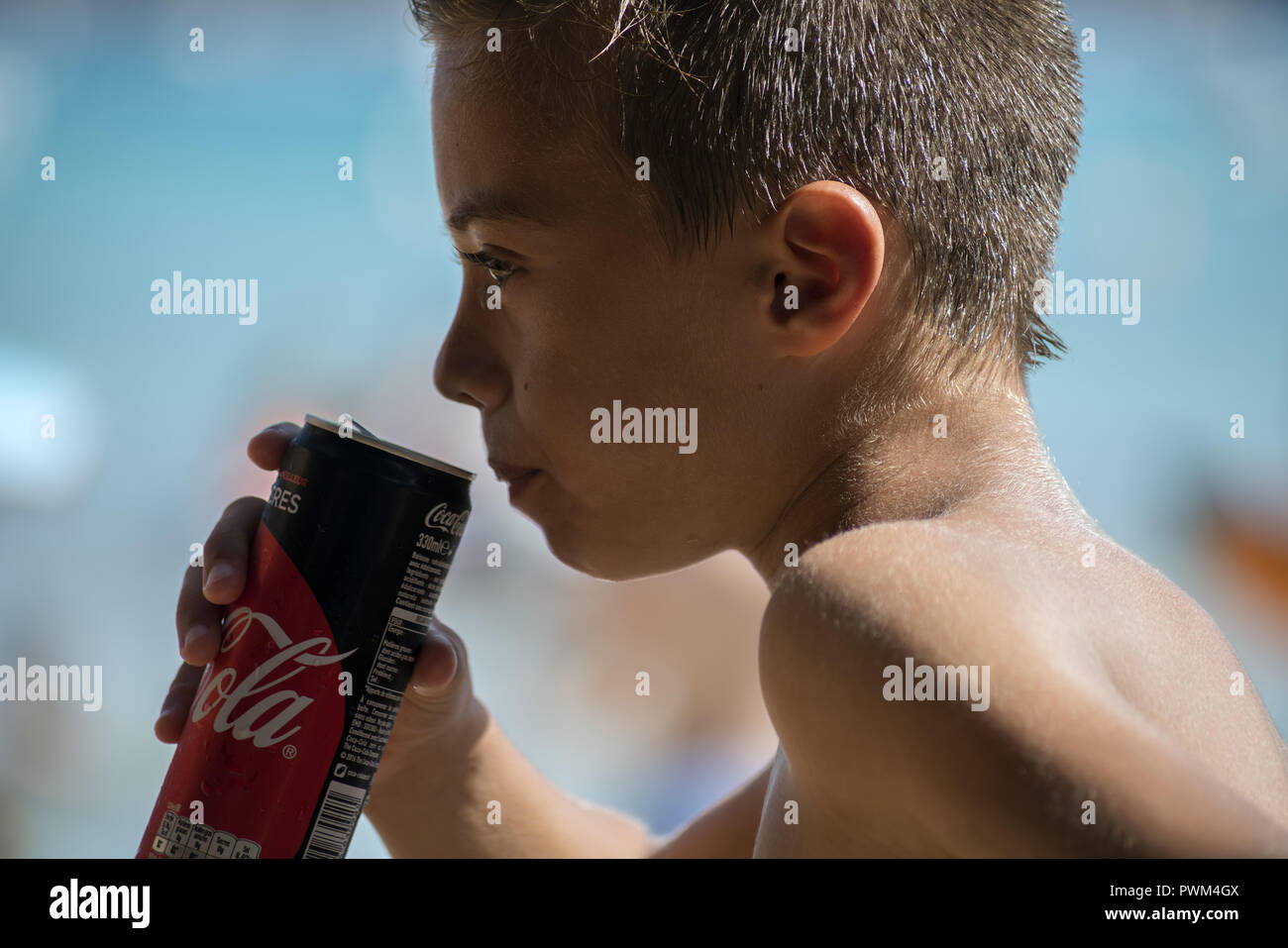 A slender boy is drinking a Coca-Cola can. Photo from profile and in ...