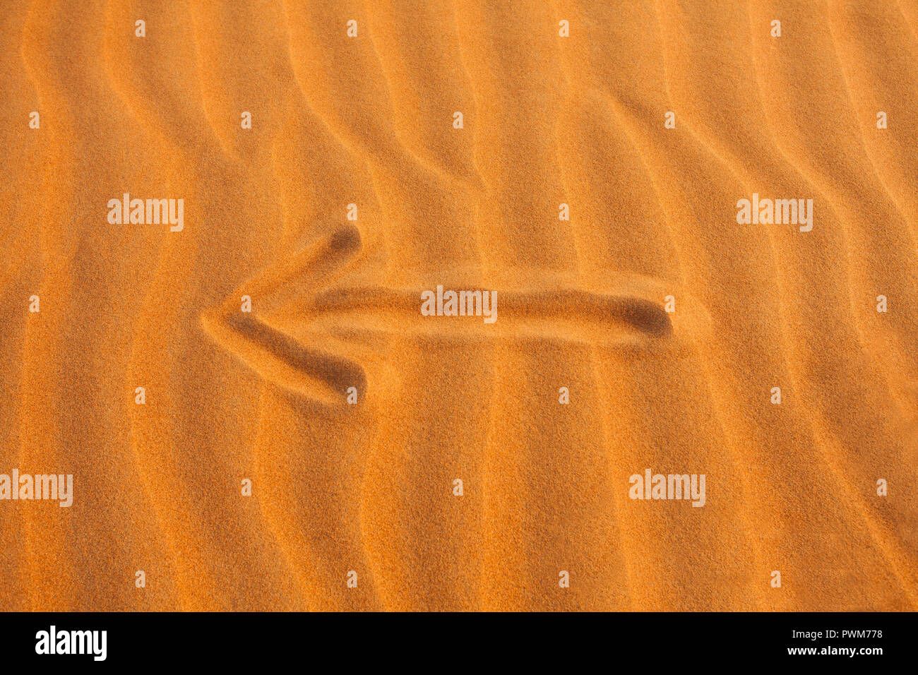 arrow in the desert sand pointing left Stock Photo - Alamy