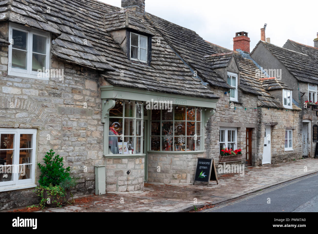 Traditional stone cottages and shops in the main street of Corfe Castle ...