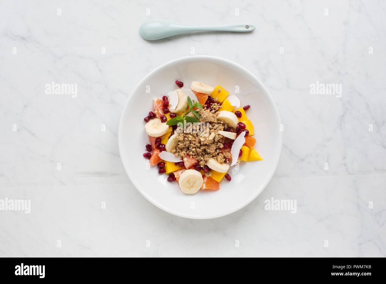 A plate of fruit with energy flakes on a marble surface (seen from ...