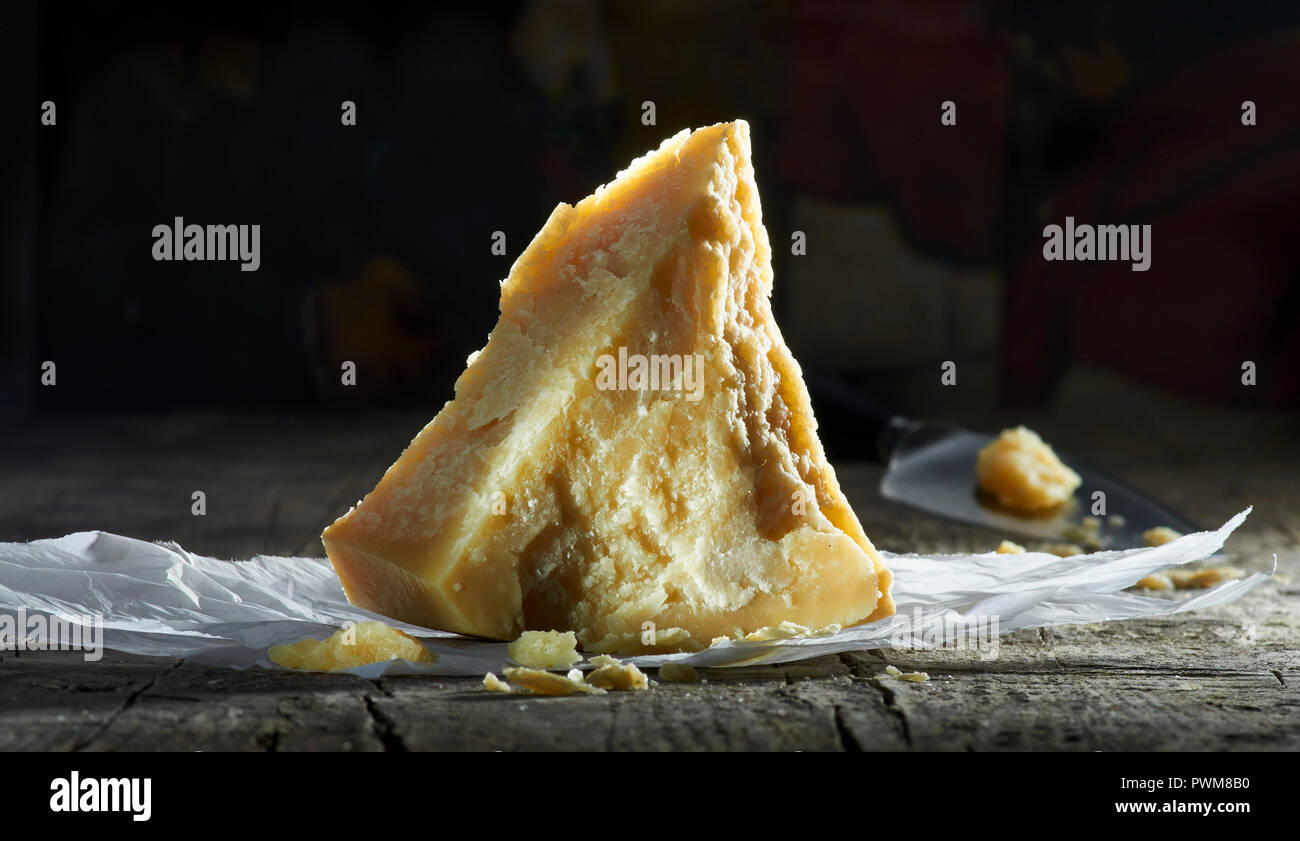 A piece of parmesan on paper next to a parmesan knife Stock Photo - Alamy