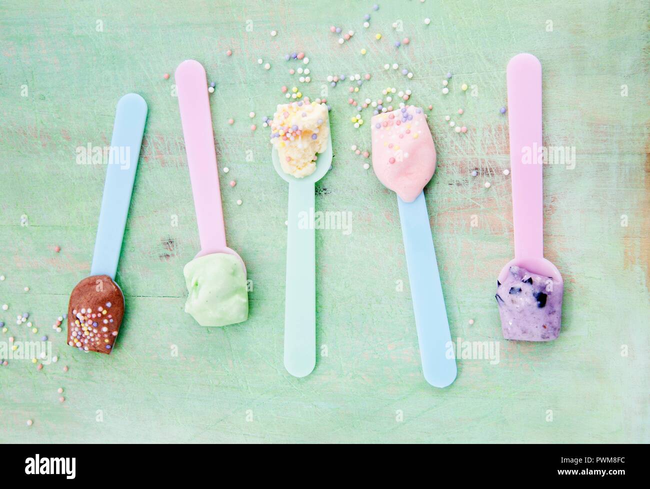 Various types of ice creams on ice cream spoons scattered with sugar pearls: vanilla, strawberry ...
