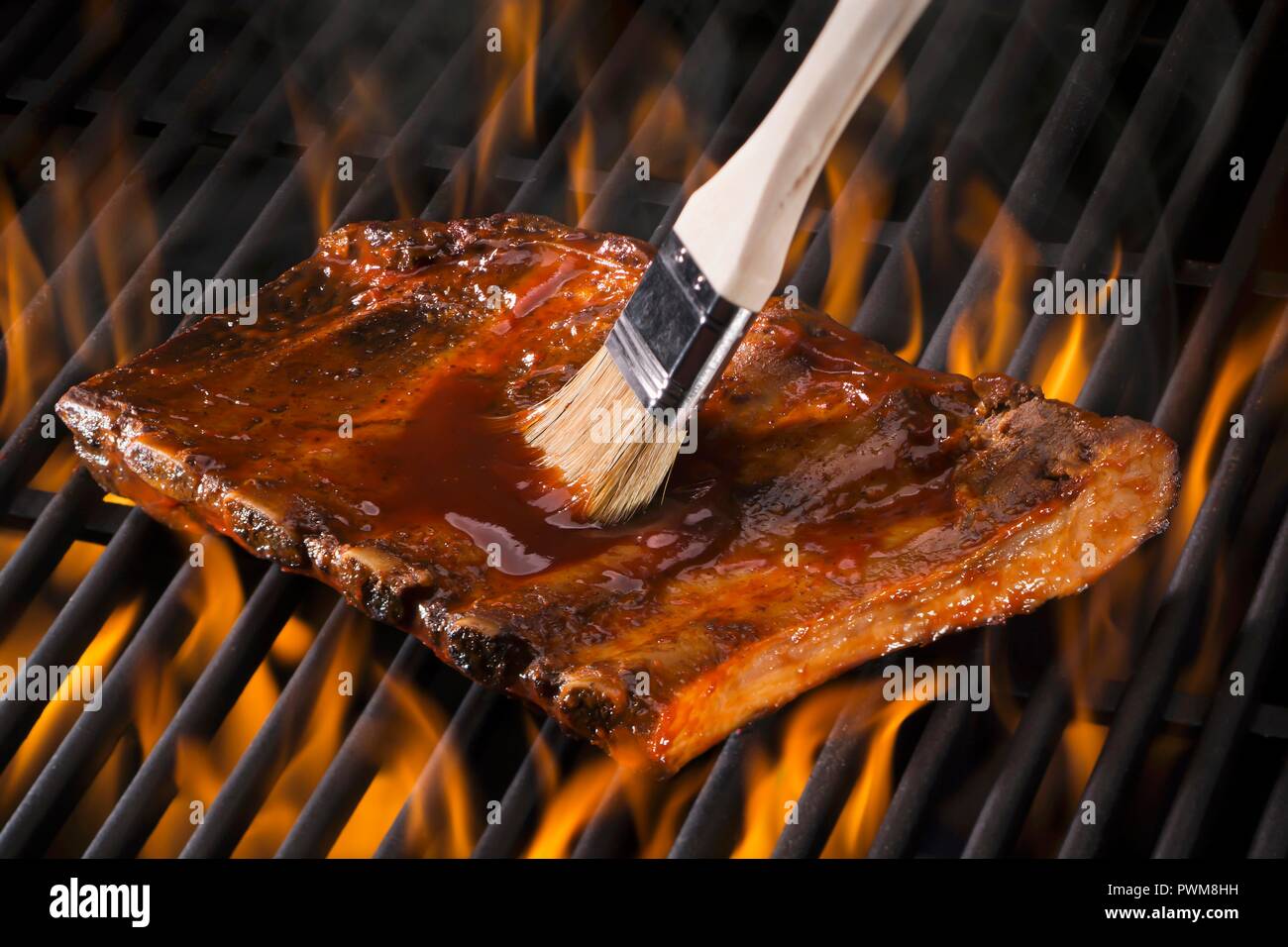 Spare ribs being brushed with marinade on a hot grill Stock Photo - Alamy