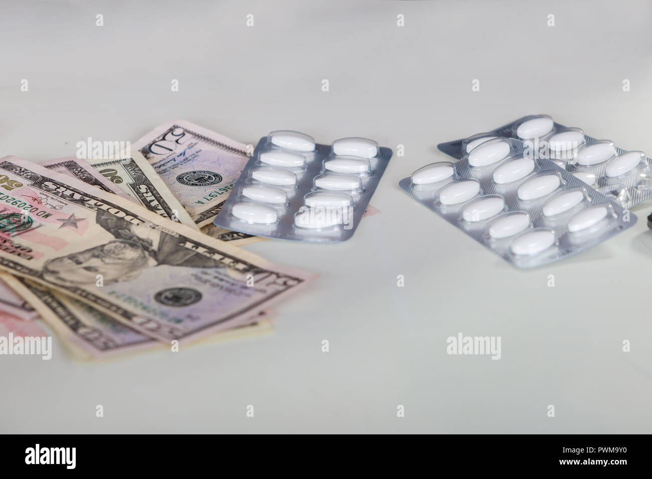 Dollar bills with close up of a with white tables falling out on top ...