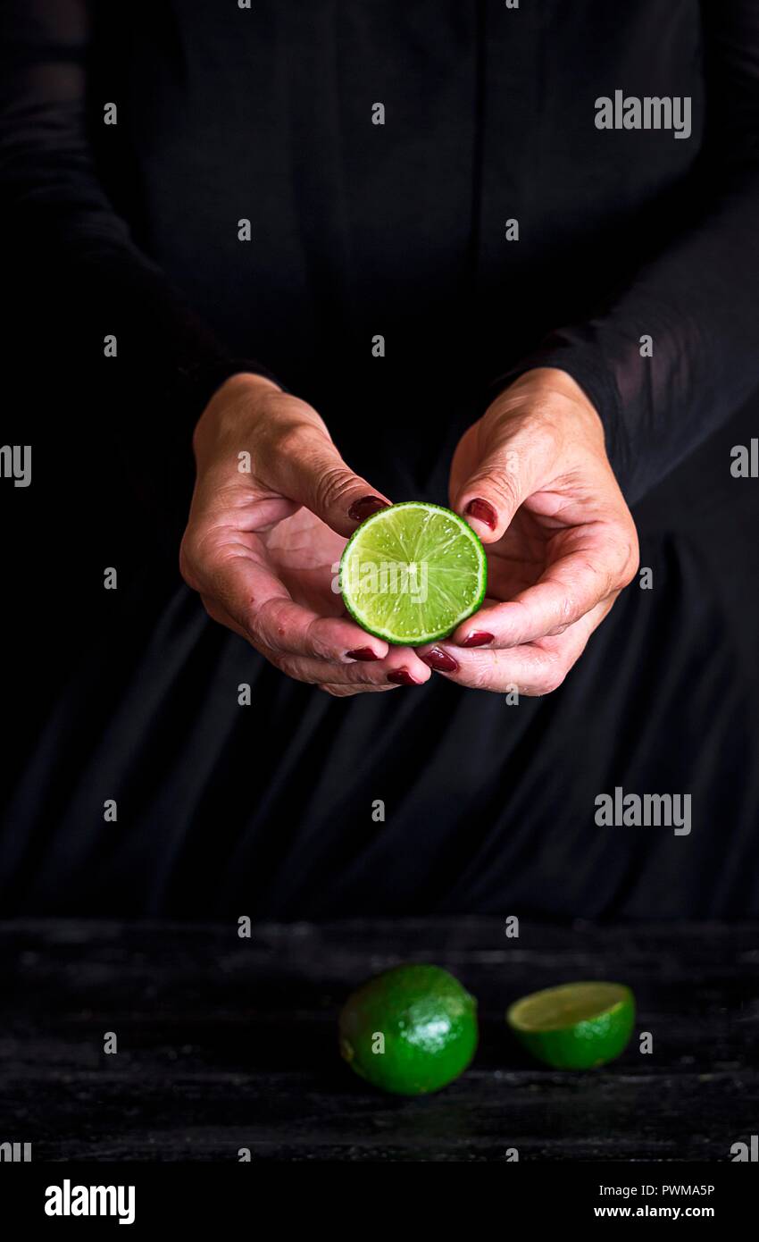 Half a lime in a woman's hands against a black background Stock Photo ...