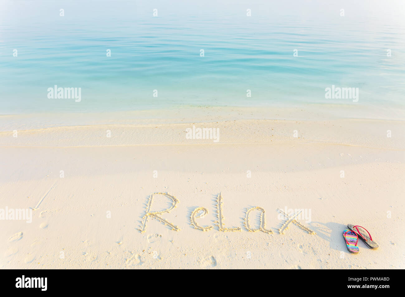 The Word Relax Written in the Sand on a Beach with flup flops at ...