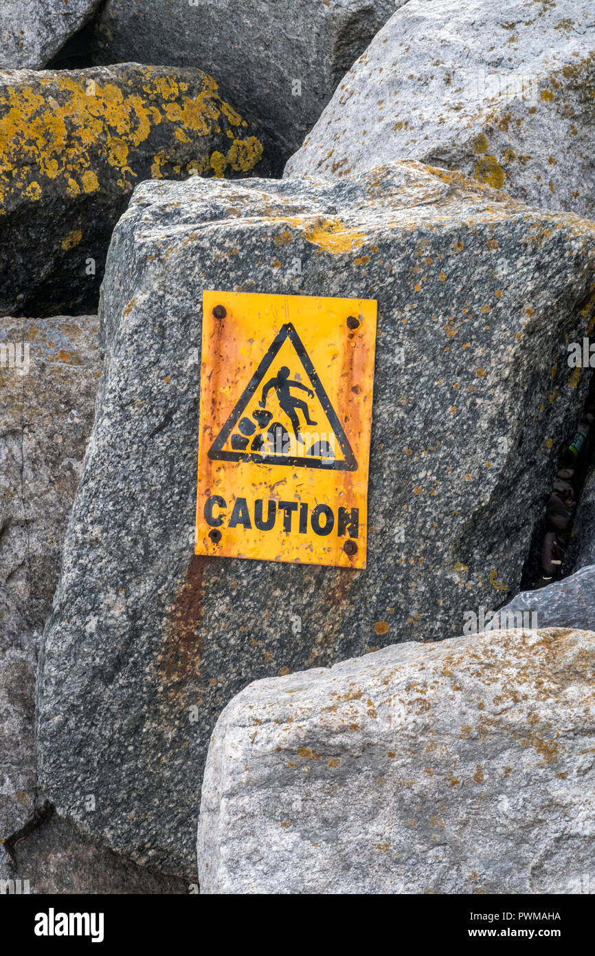 Caution, Slippery rocks sign on rock groynes in Sidmouth, Devon Stock ...