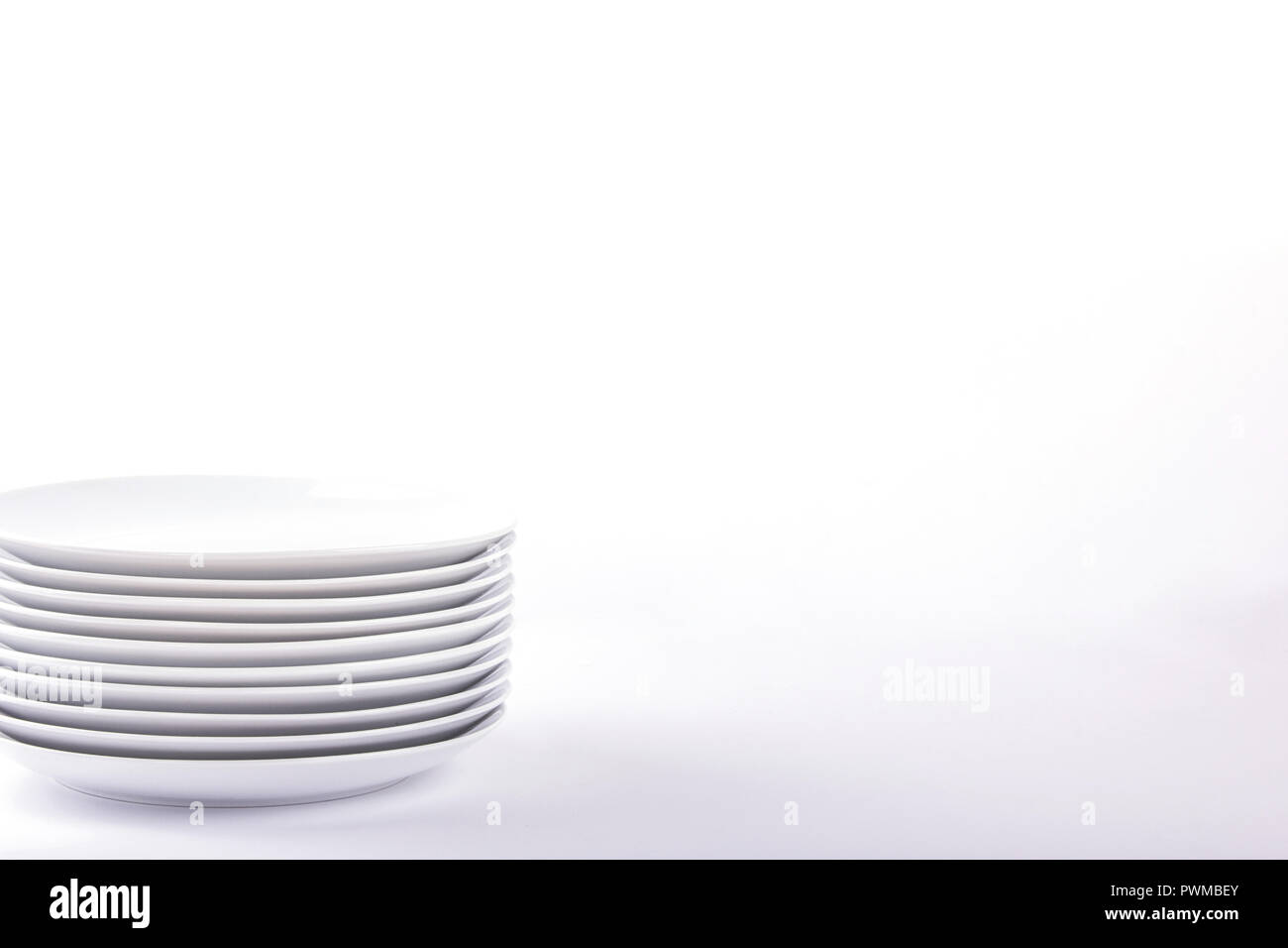 Stacked white plates on white background Stock Photo - Alamy