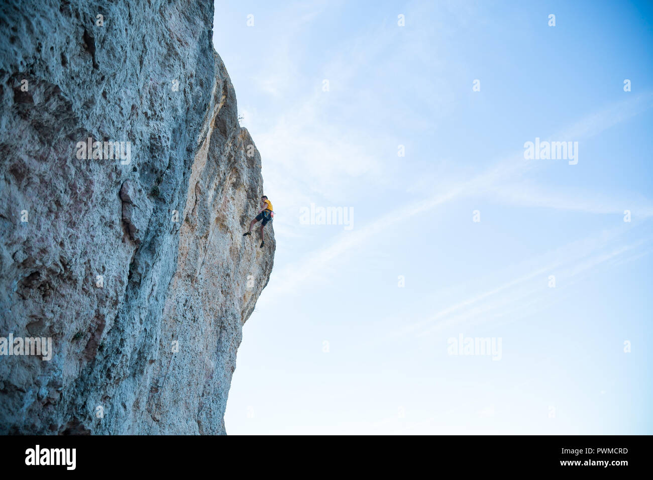 View of man without helmet hanging on a rope while rappelling and shows ...