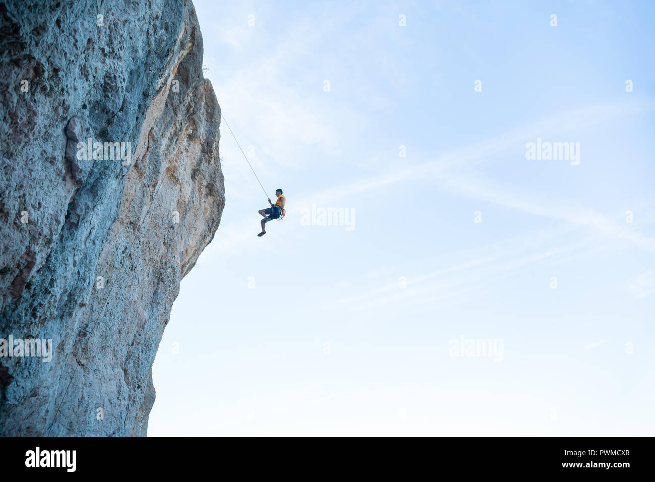 View of man without helmet hanging on a rope while rappelling and shows ...