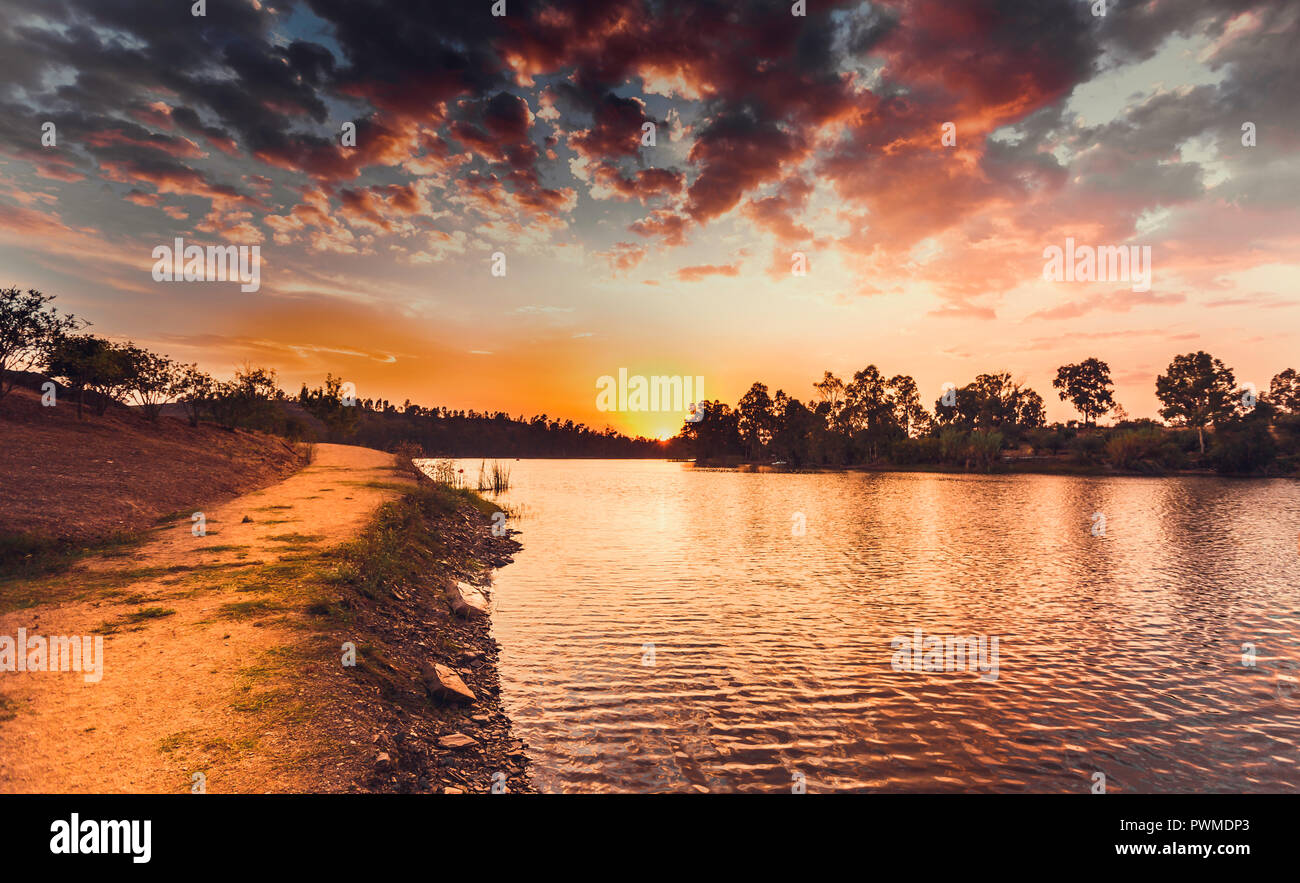 Great sun on the horizon illuminating the road and the water of the ...