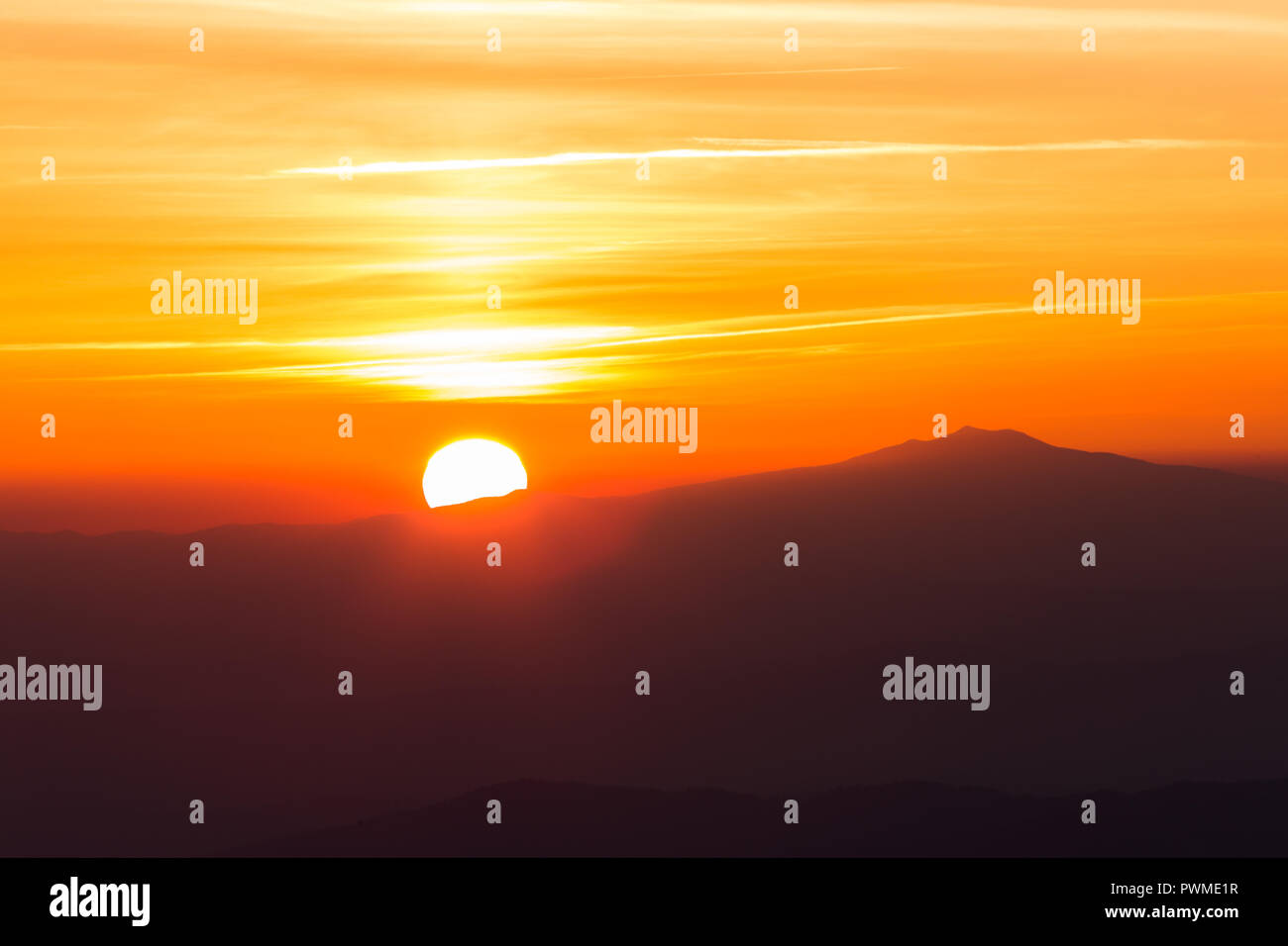 Beautiful sunset with sun coming down behind various layers of ...