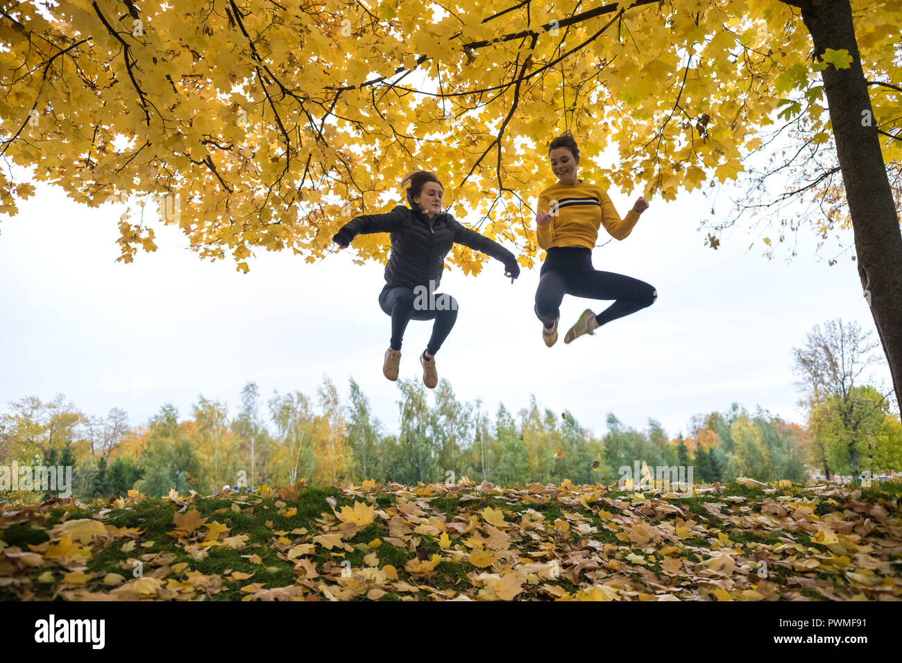 Autumn photo of sporty women jumping in forest at morning against ...