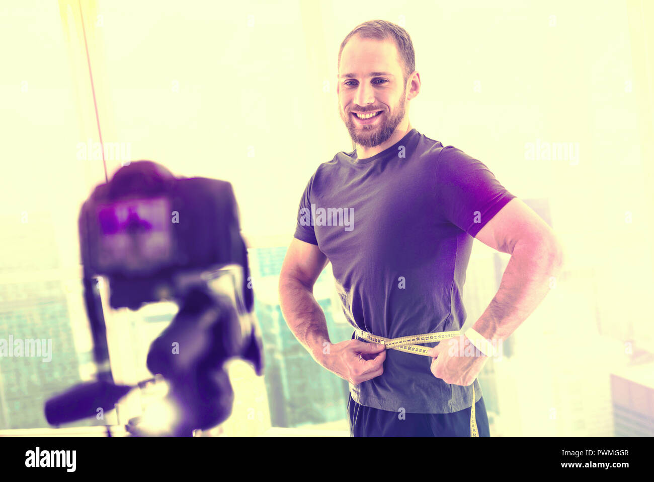 Joyful handsome man measuring himself in front of the camera Stock ...