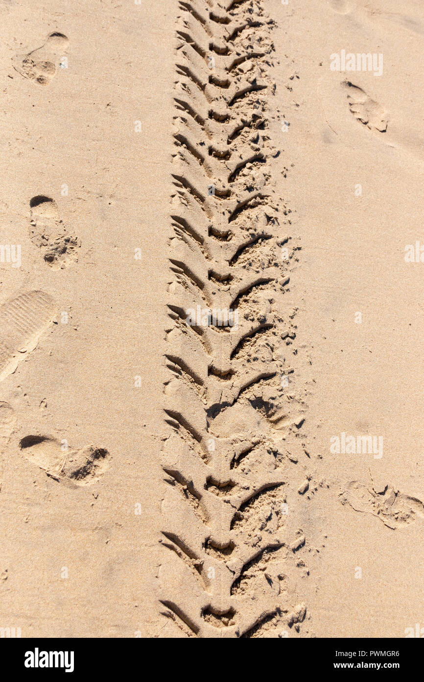 A close up view of a tractor's tyre tracks left behind in the beach ...