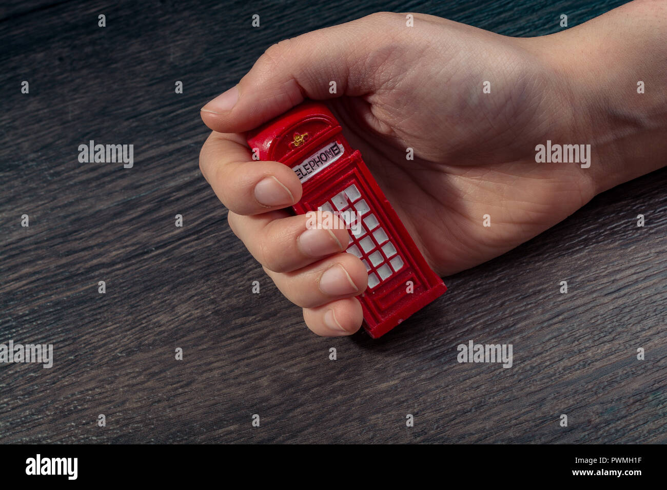 Hand holding a phone booth on a brown background Stock Photo - Alamy