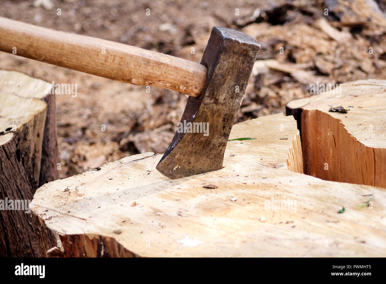 An axe on a wood, tree log. An axe stuck in a log in front of a pile of ...
