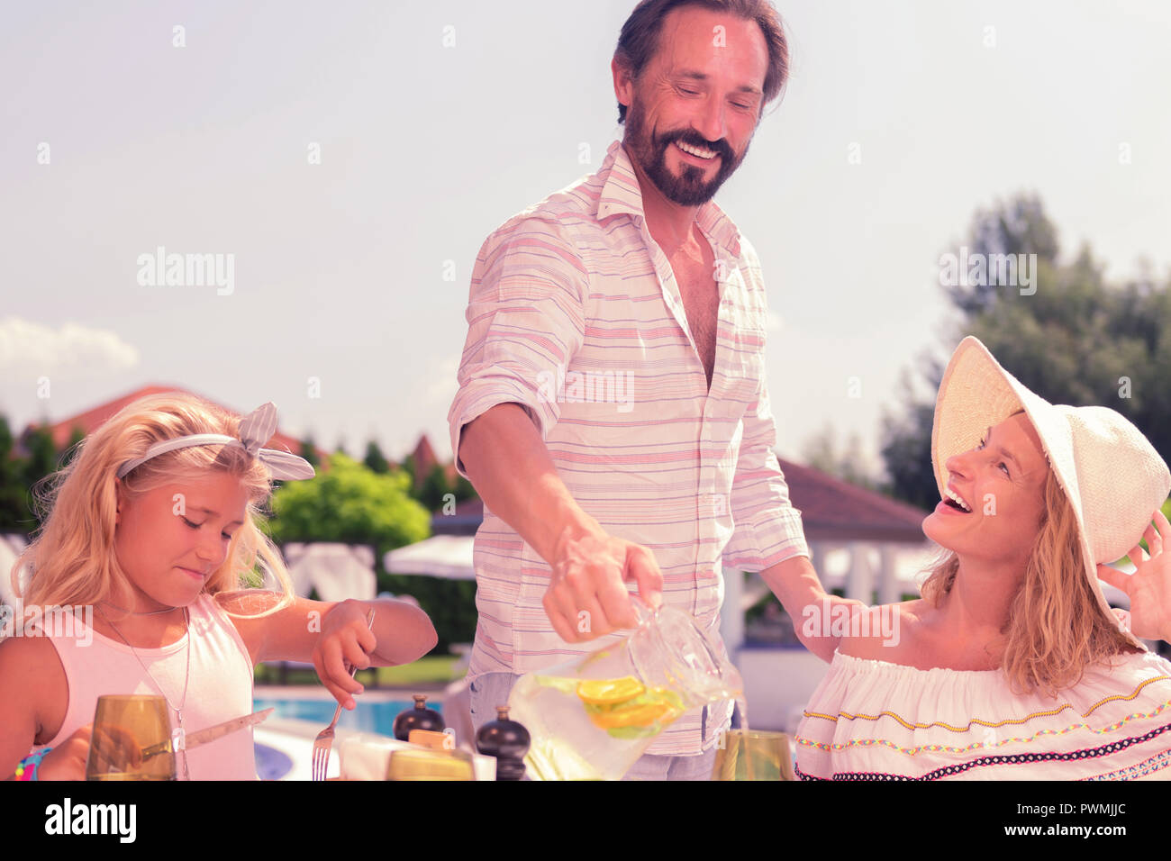 Positive caring man pouring lemonade in the cup Stock Photo - Alamy